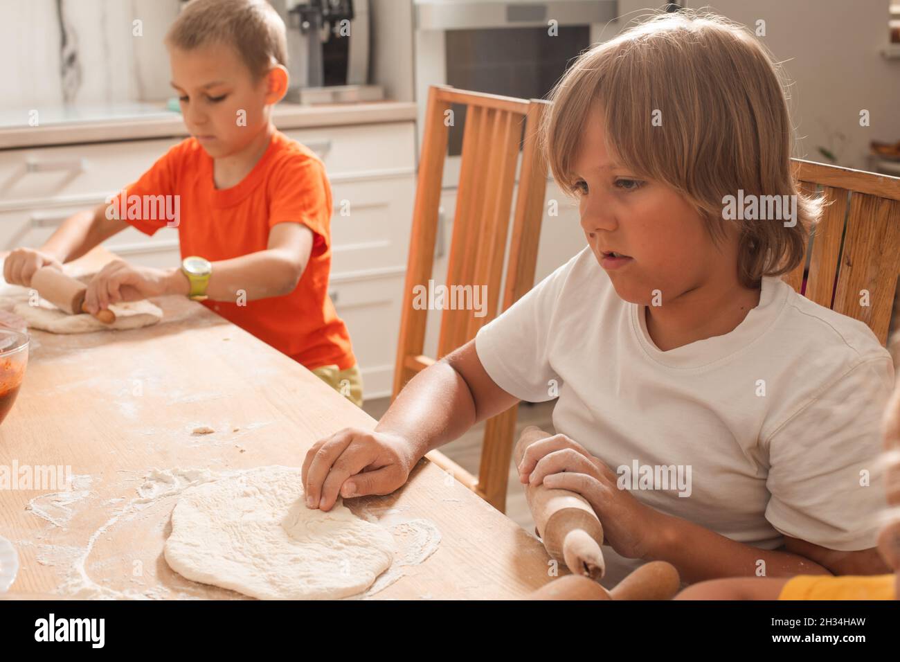 The children sit at a table in the kitchen and make pizza Stock Photo ...