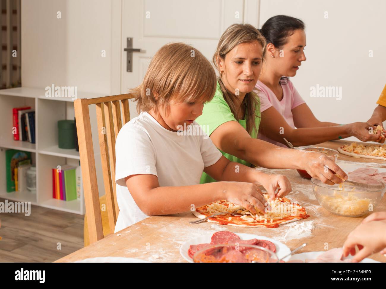 Group of people sit at a table in the kitchen and make pizza Stock ...
