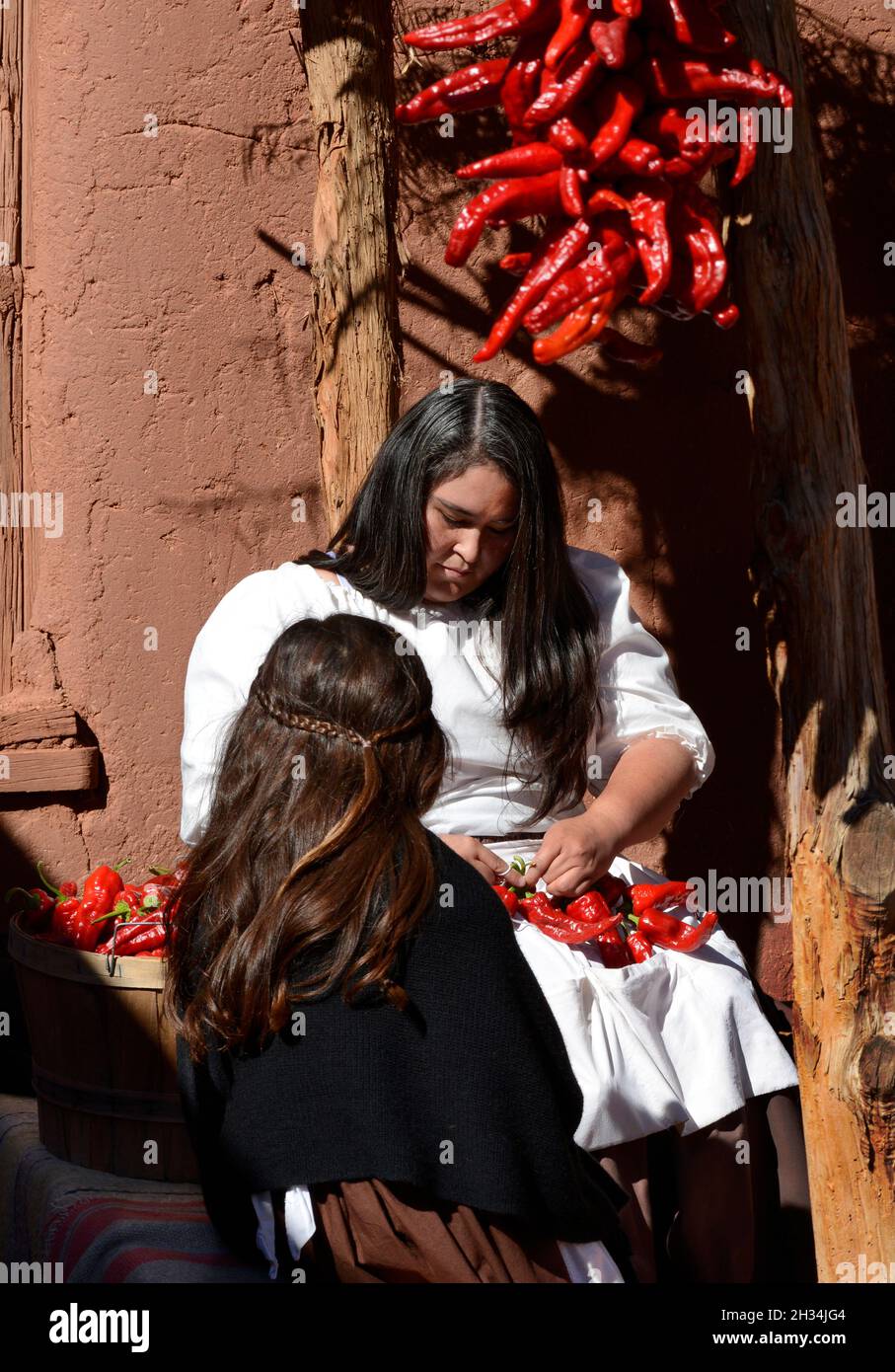 A woman demonstrates how to make traditional ristras by stringing red ...