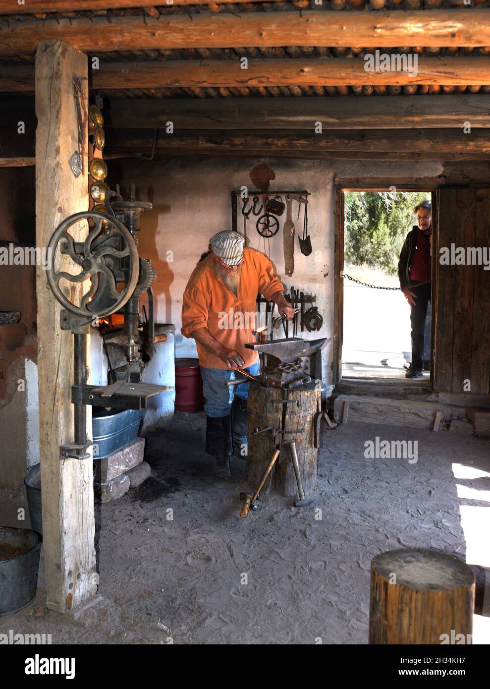 A blacksmith works with an iron and an anvil in the blacksmith shop at ...