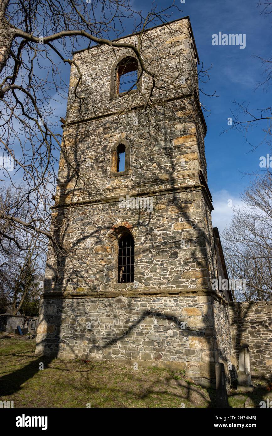 A half-demolished stone church behind the enclosure wall with blue sky ...