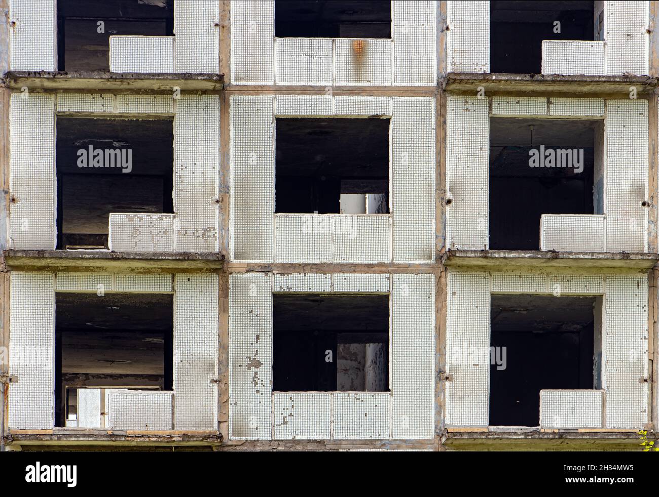 A damaged abandoned panel house with decorative facade of small white ...