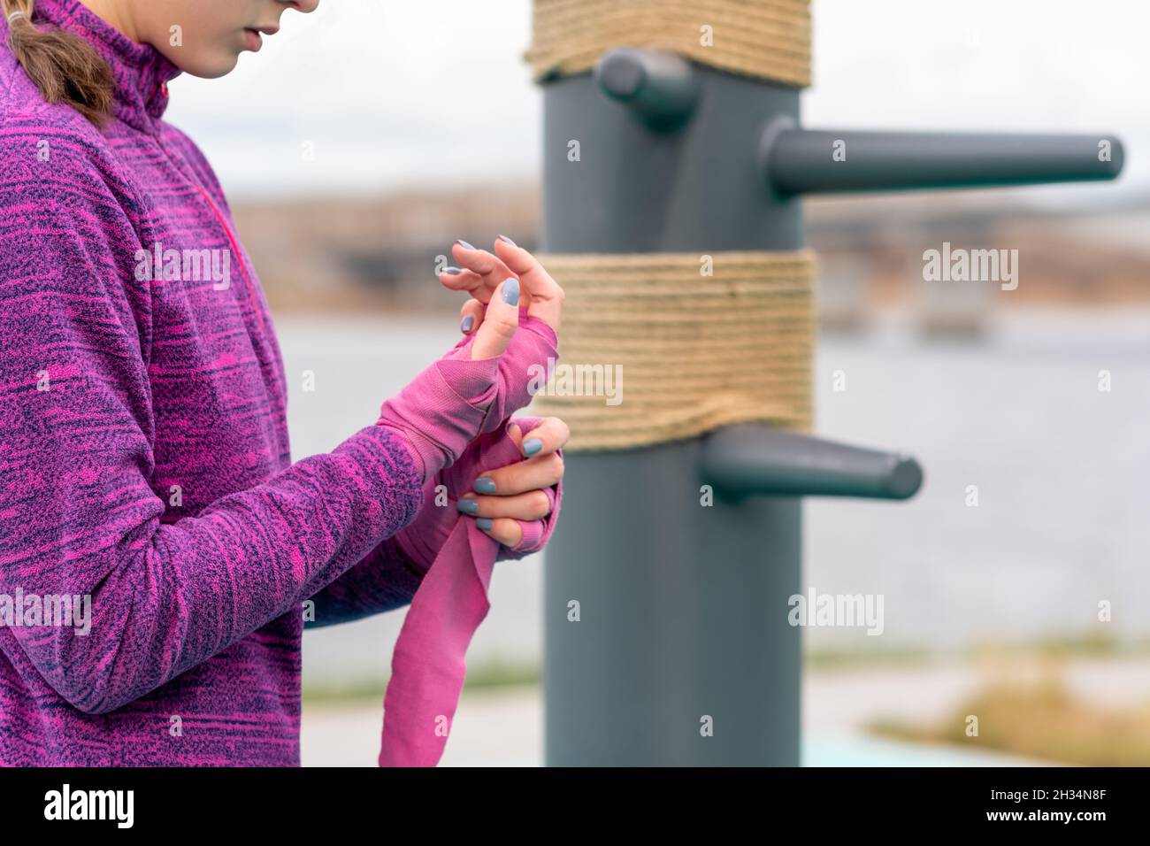 girl wrapping a wrist wrap around her hand before outdoor martial arts ...