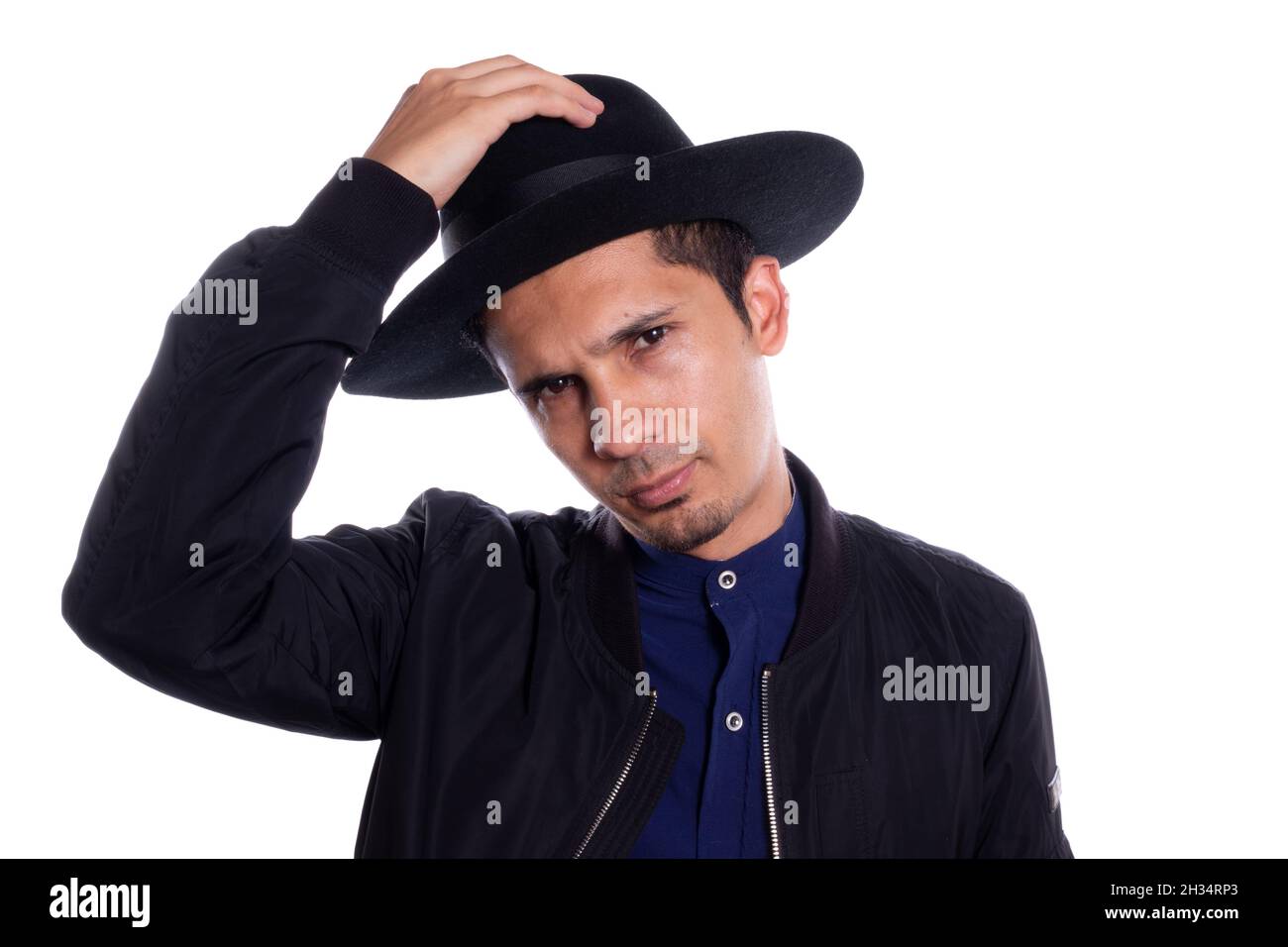 Man putting on black hat on white background. Young Latino man wearing ...