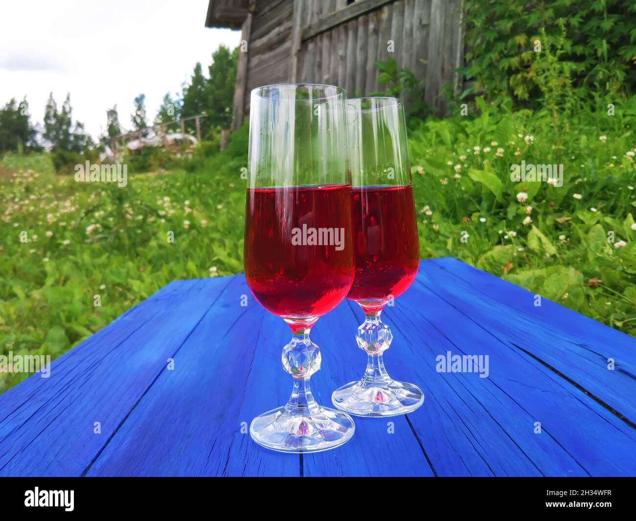 Two glasses with homemade red vine on blue boards outdoors in ...