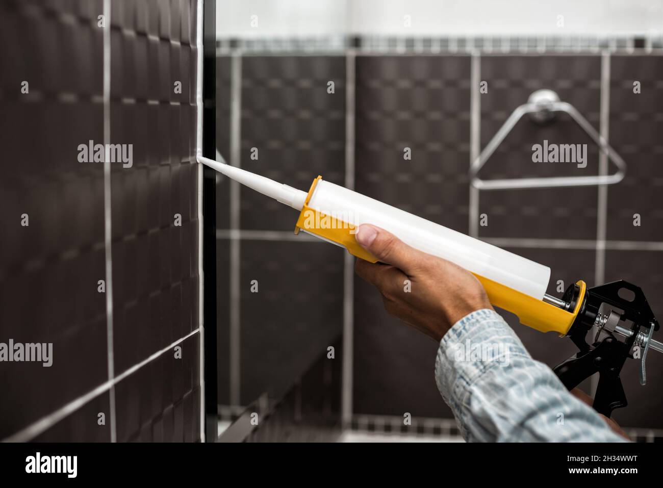 The man applying silicone sealant. The man fixing home Stock Photo - Alamy