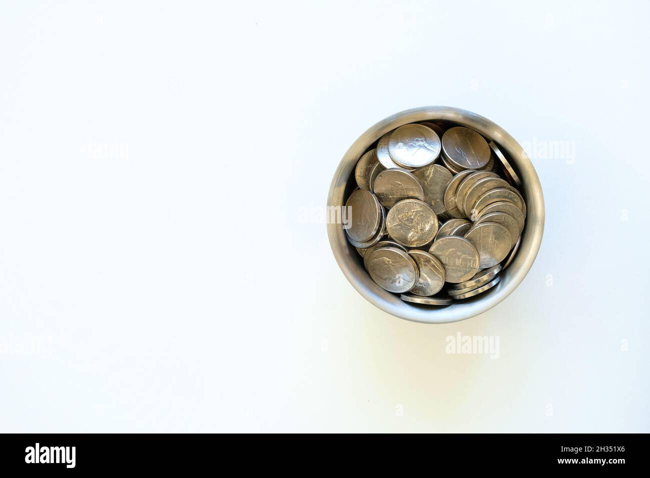 Assorted selection of current use American nickels in a chrome cup on a ...
