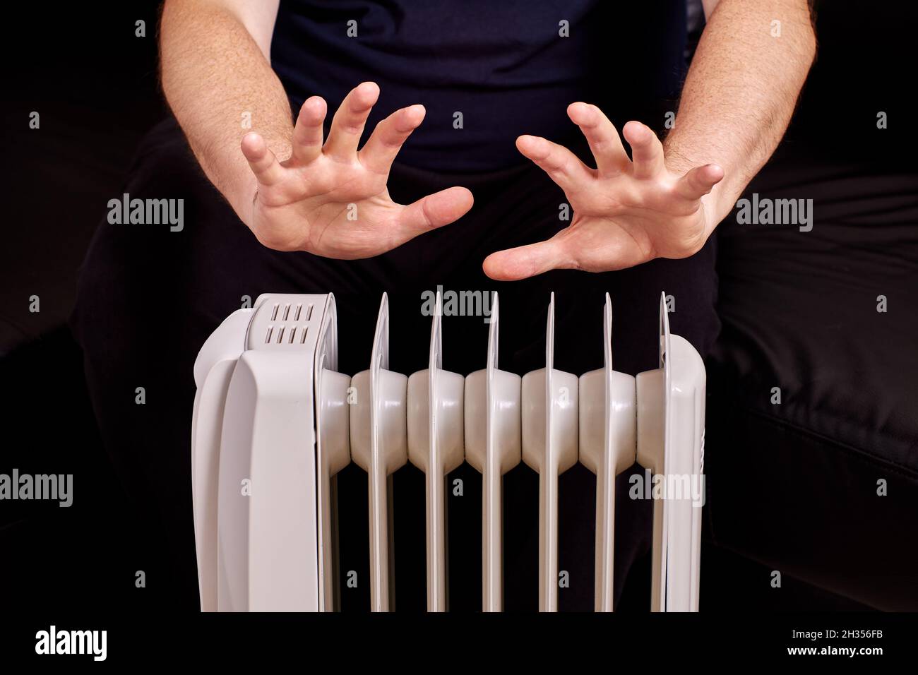 Electric heater with man who is warming his hands near Stock Photo - Alamy