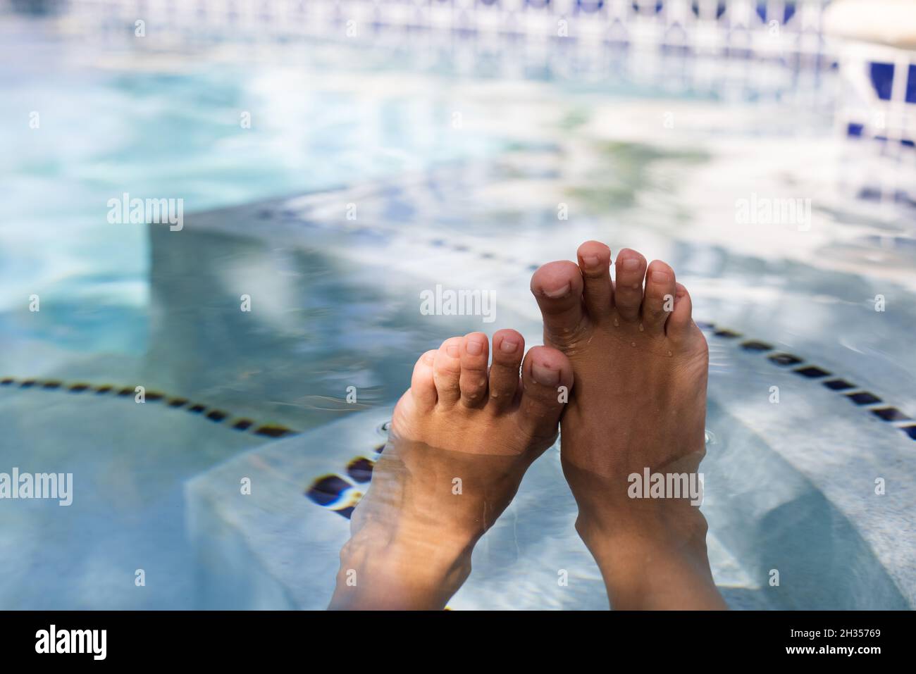 Female feet in water in swimming pool, closeup. Woman relaxing near ...