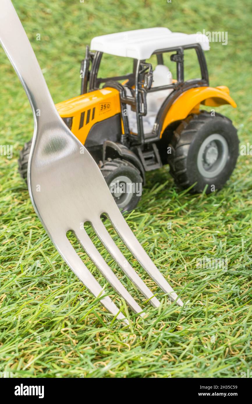 Small toy tractor on faux / fake grass with stainless steel fork tines ...