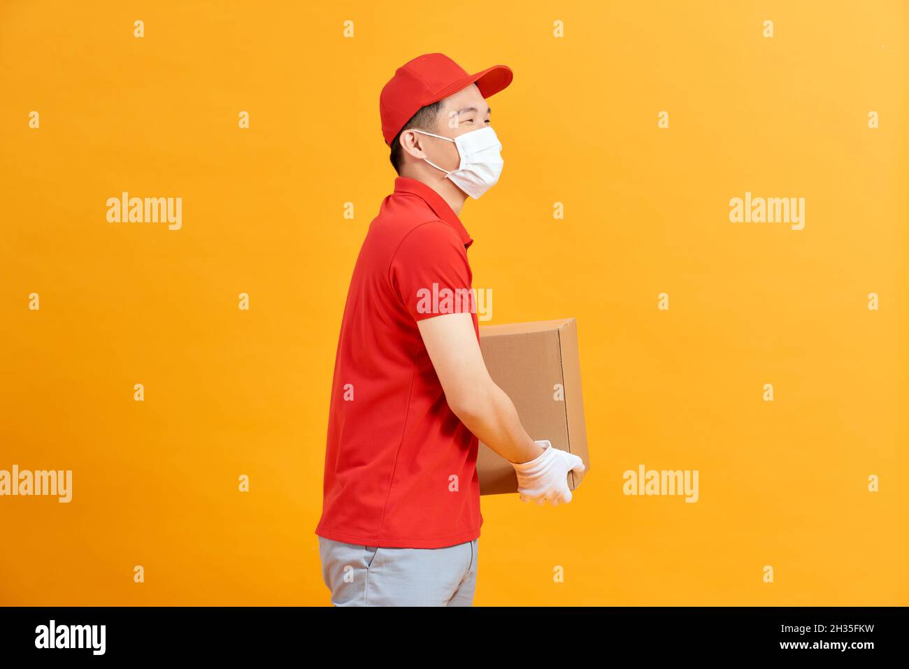 Delivery man employee in red cap blank t-shirt uniform face mask gloves ...