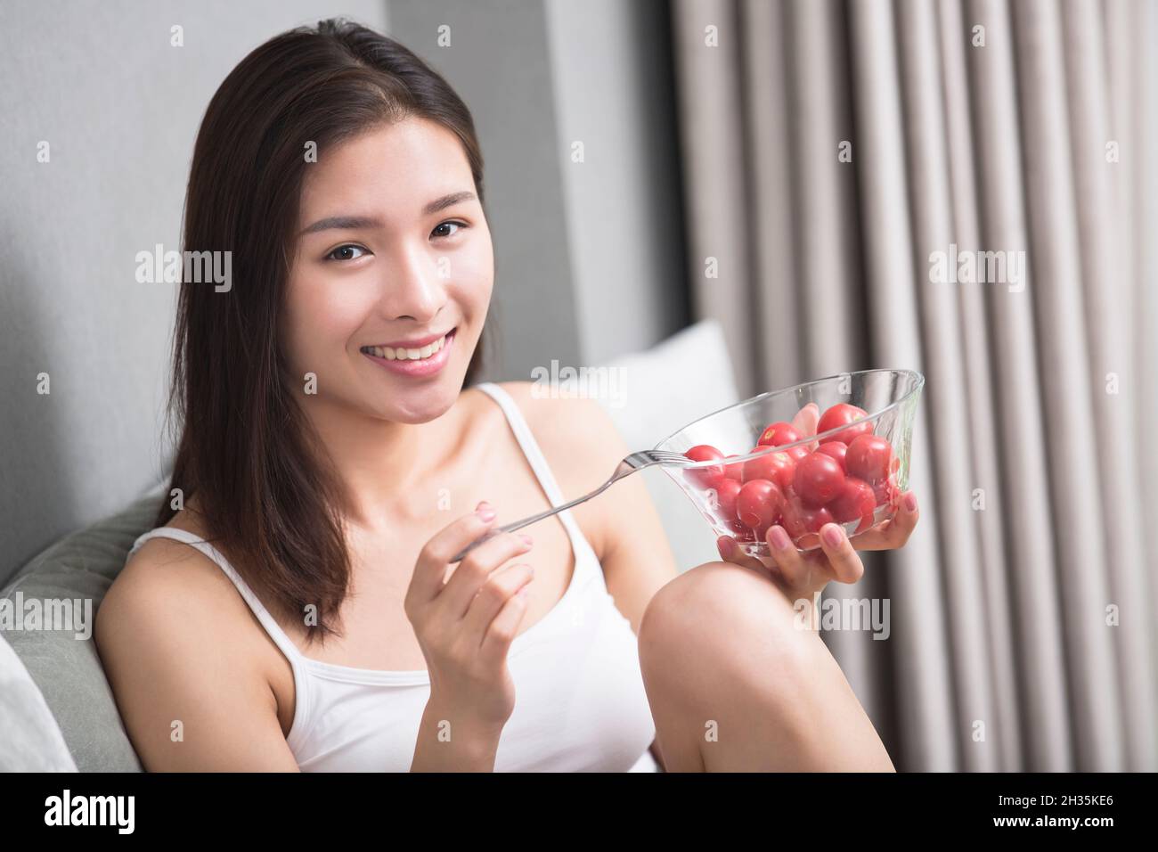 Beautiful young woman eating fruit Stock Photo - Alamy