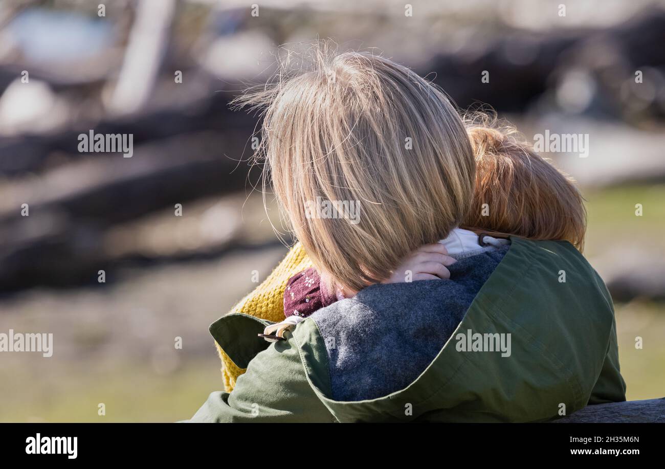 Rear view of a mother embrace her small child outdoor in the park ...