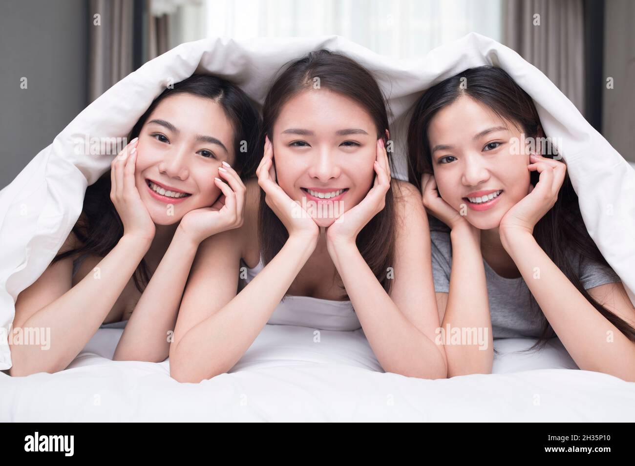 Three young women lying on bed hi-res stock photography and images - Alamy