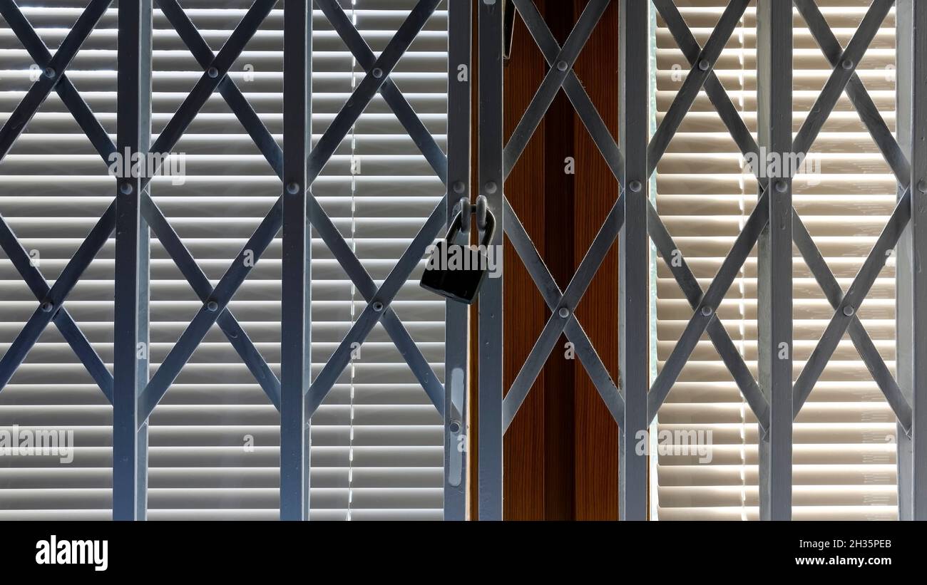 Steel folding grating in front of a closed window blind visible from ...