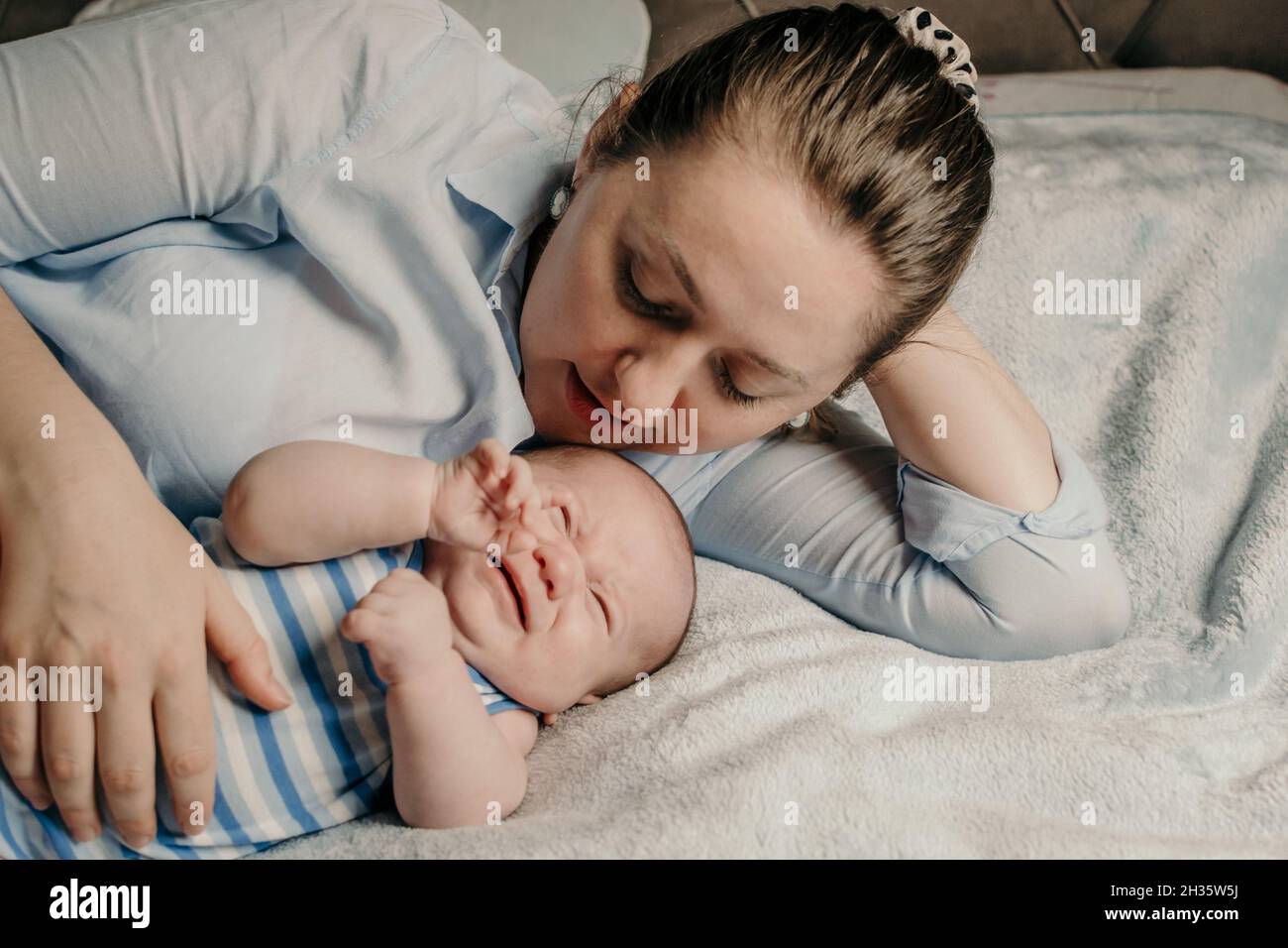 Young mother cuddling with her newborn baby boy in bed Stock Photo - Alamy