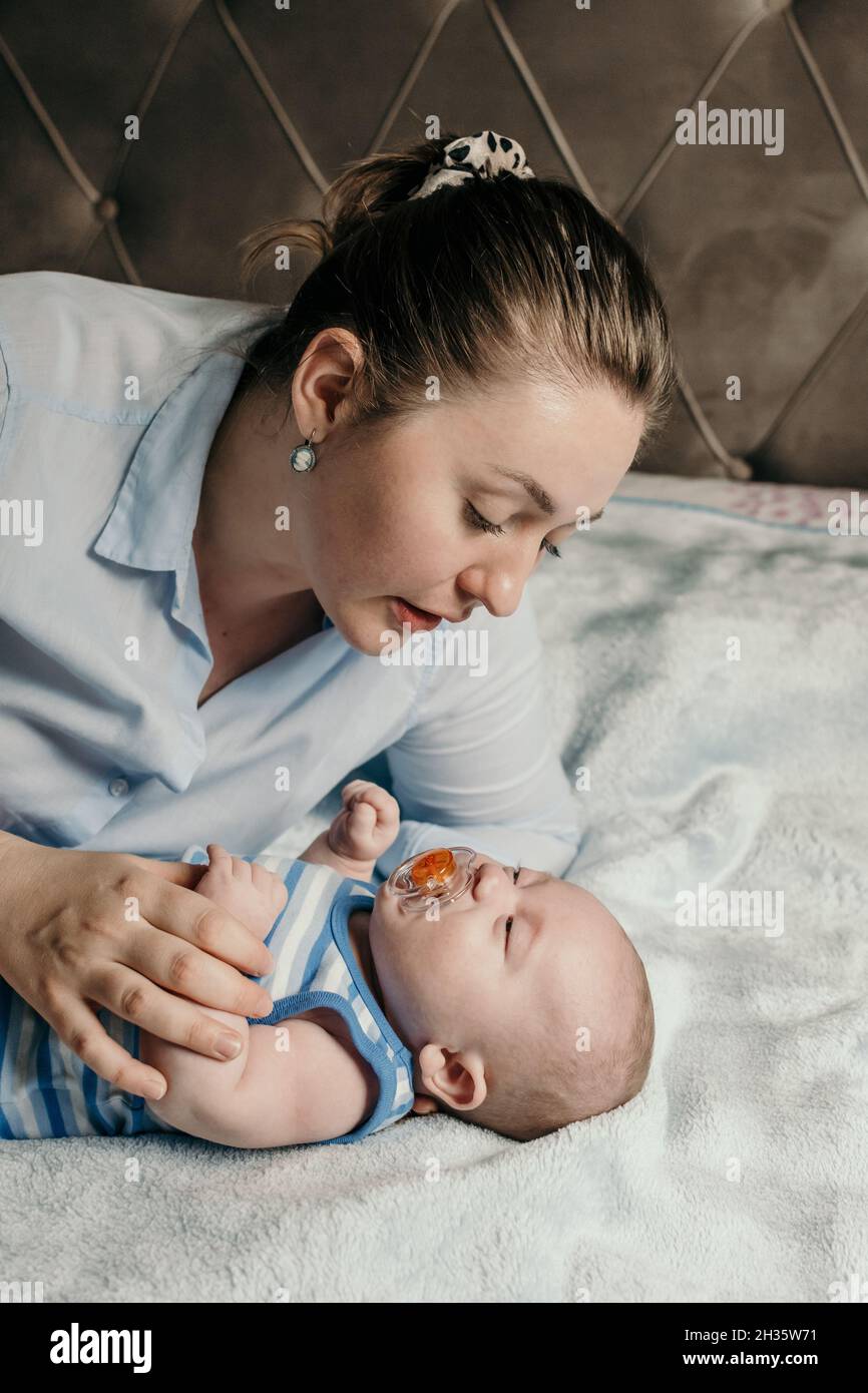 Young mother cuddling with her newborn baby boy in bed Stock Photo - Alamy
