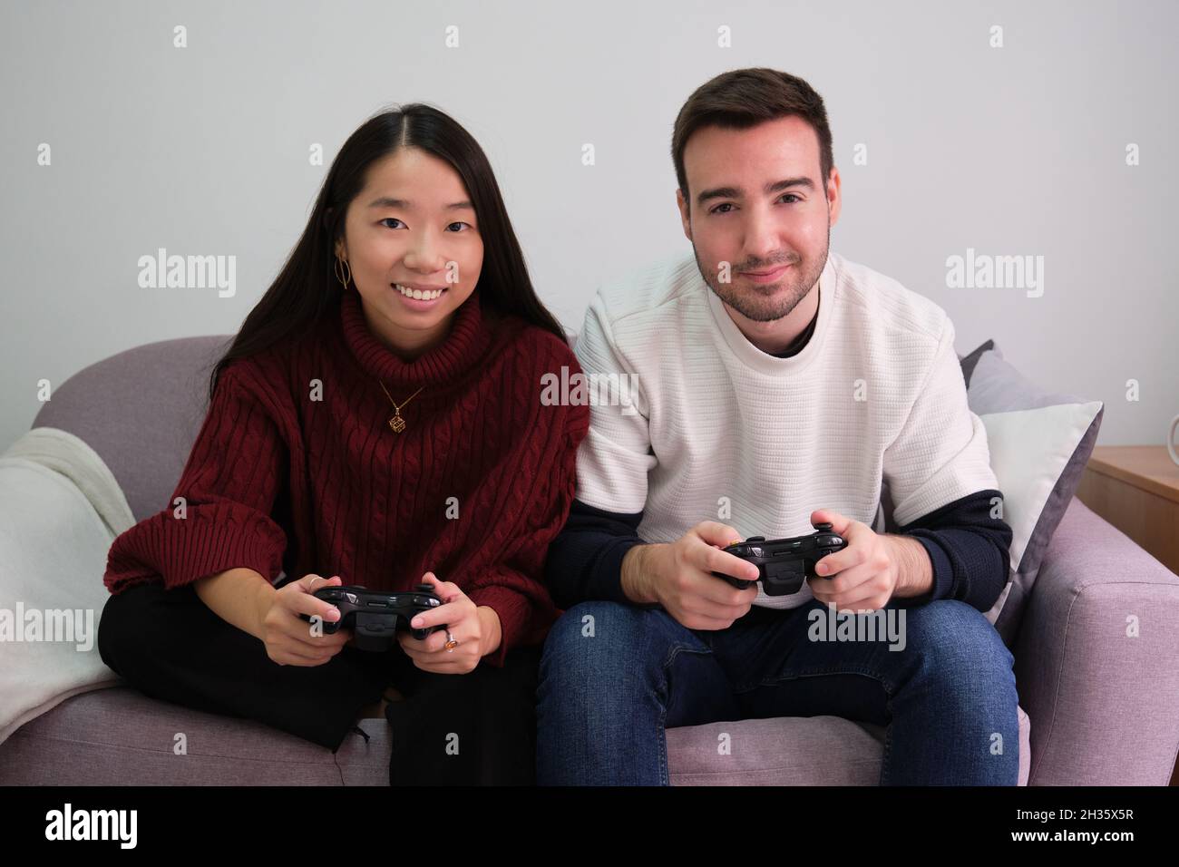 Young multiracial couple playing video games and using joystick ...