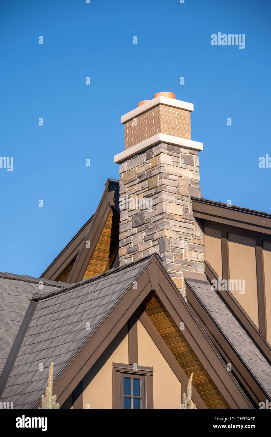 Vertical view of a brick chimney of modern house against the blue sky ...
