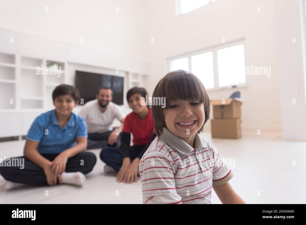 portrait of happy young boys with their dad sitting on the floor in a ...