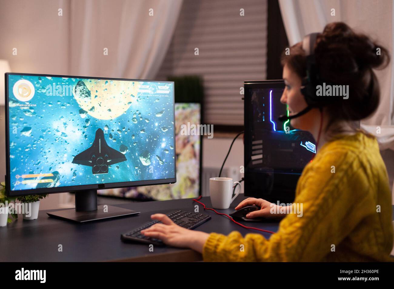 Focused woman gamer with headphones playing space shooter videogames ...