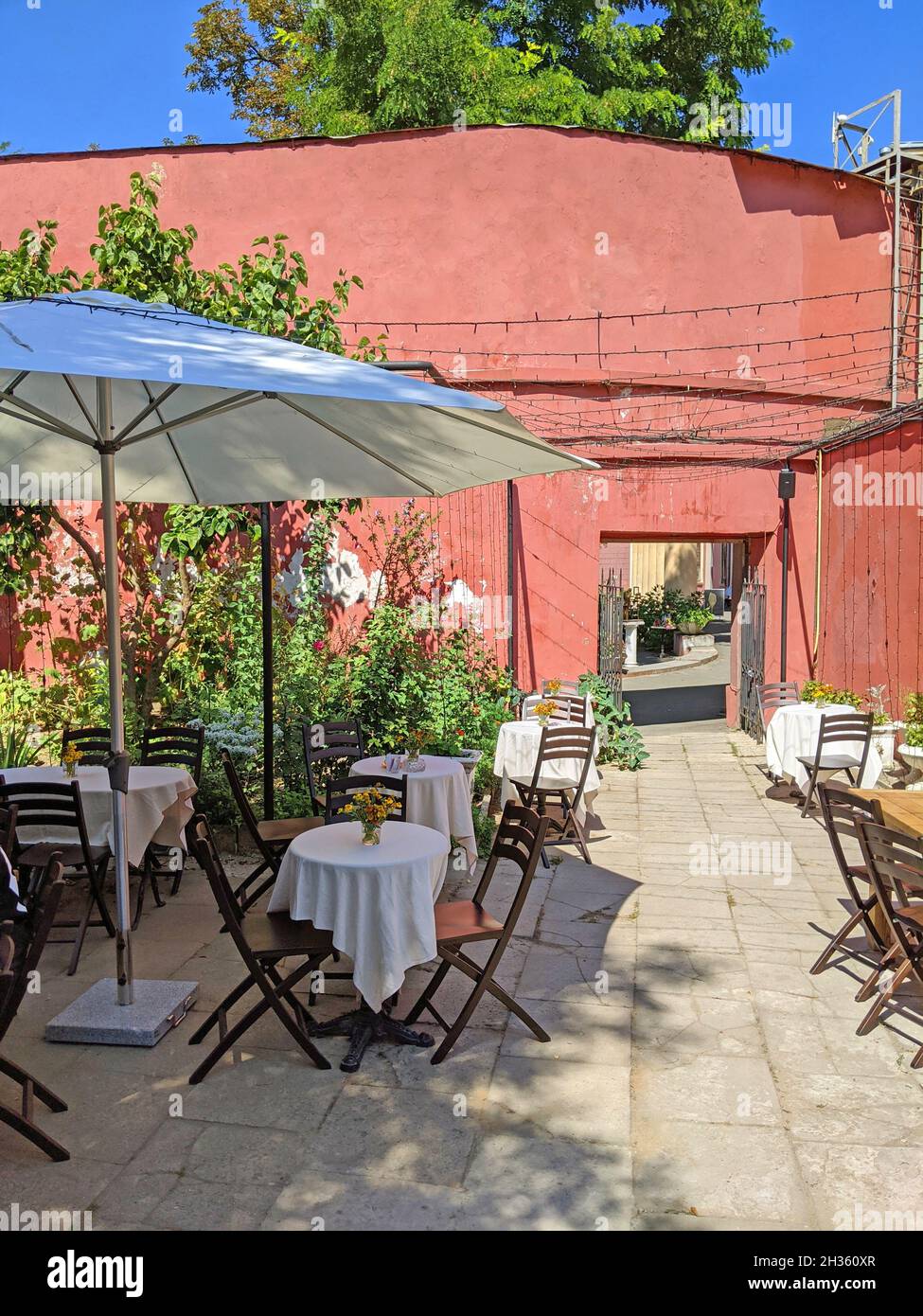 Outdoor cafe terrace with wooden chairs and tables in the shade of ...