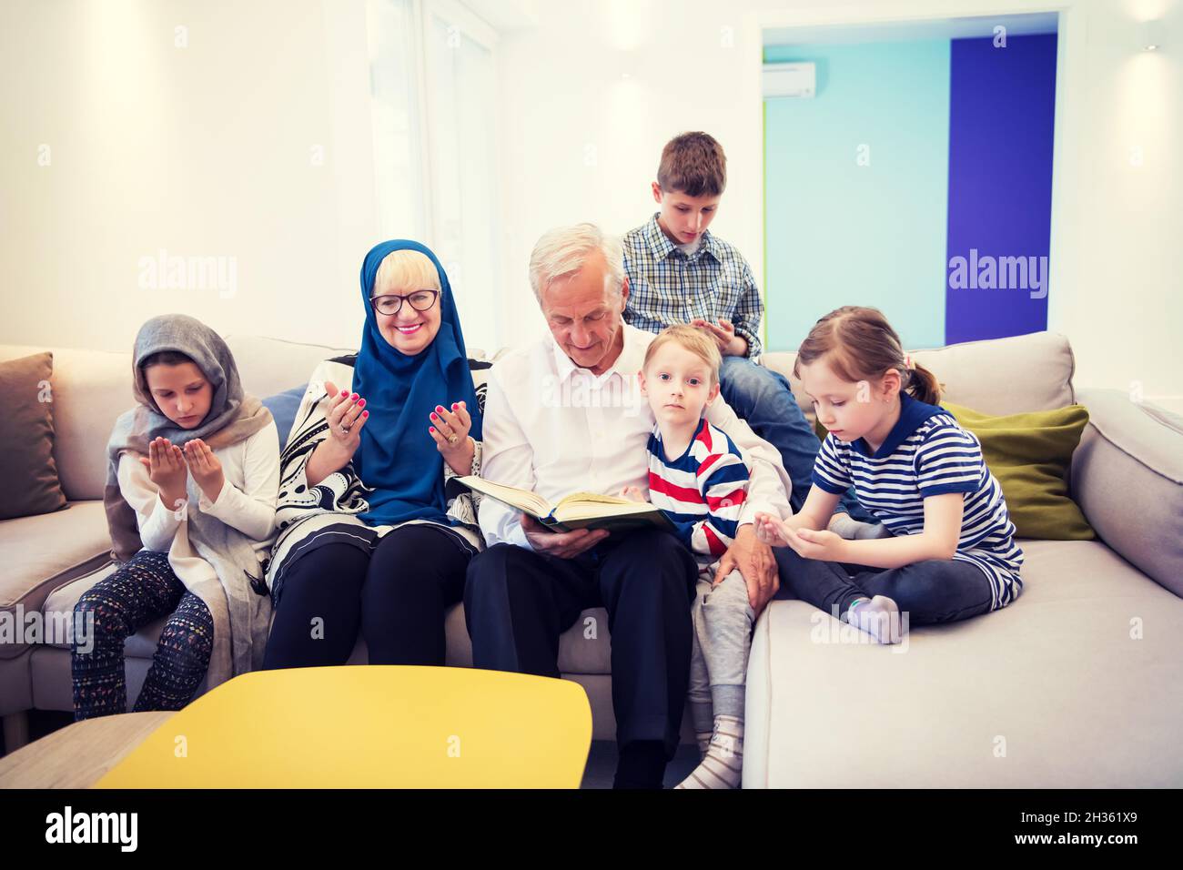 modern muslim family grandparents with grandchildren reading Quran and ...