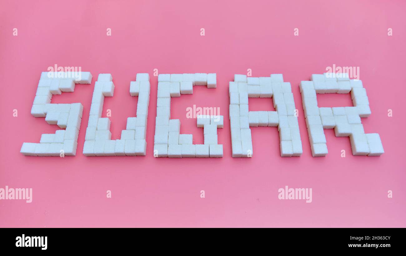 The word sugar from white refined pieces on a pink background Stock ...