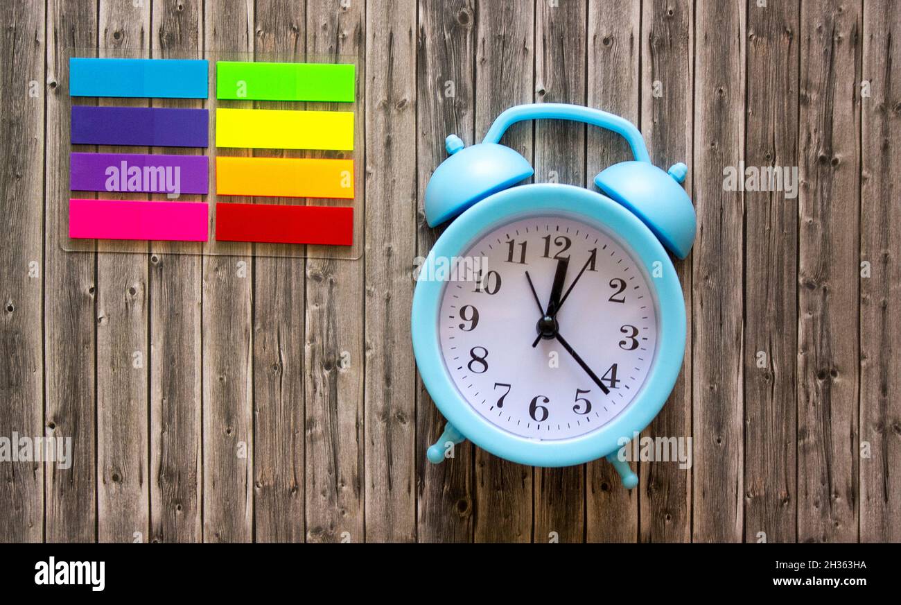 Clock and color stickers on wooden background Stock Photo - Alamy