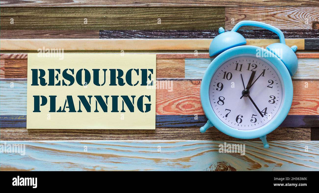 Alarm clock and note sticker on desk with text Resource planning. Time ...