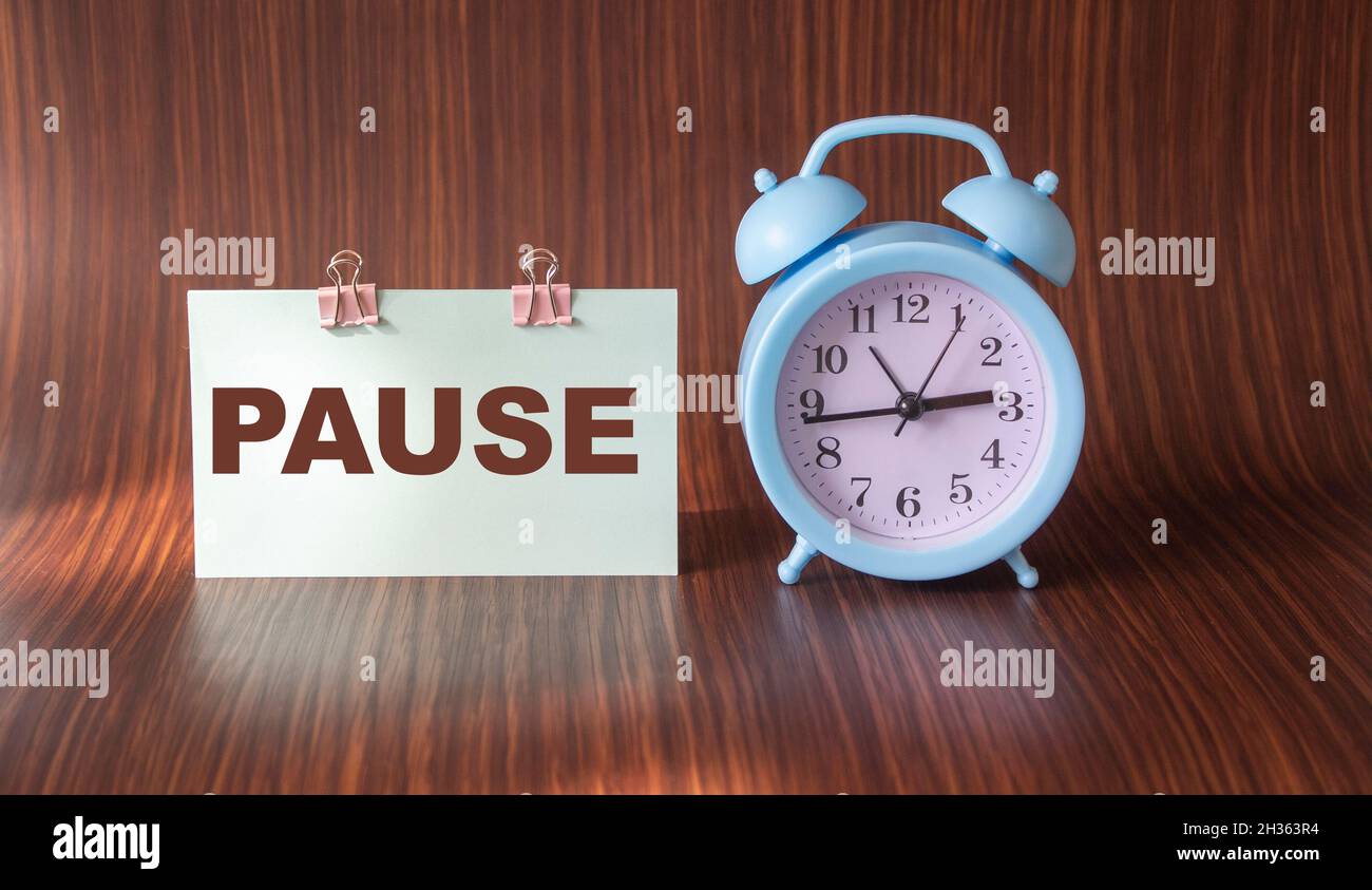 Table clock on a wooden background with the inscription Pause Stock ...