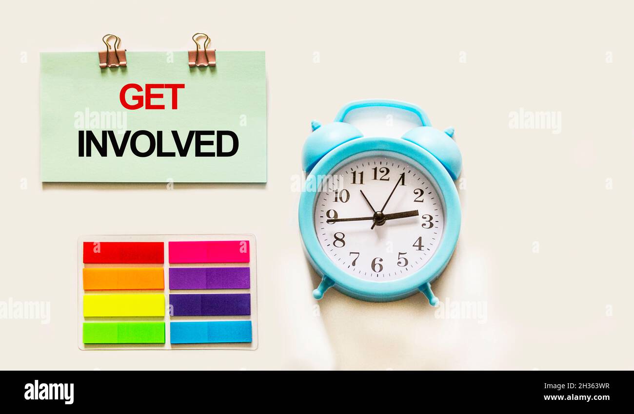 Get involved text written on sticker next to alarm clock on white ...