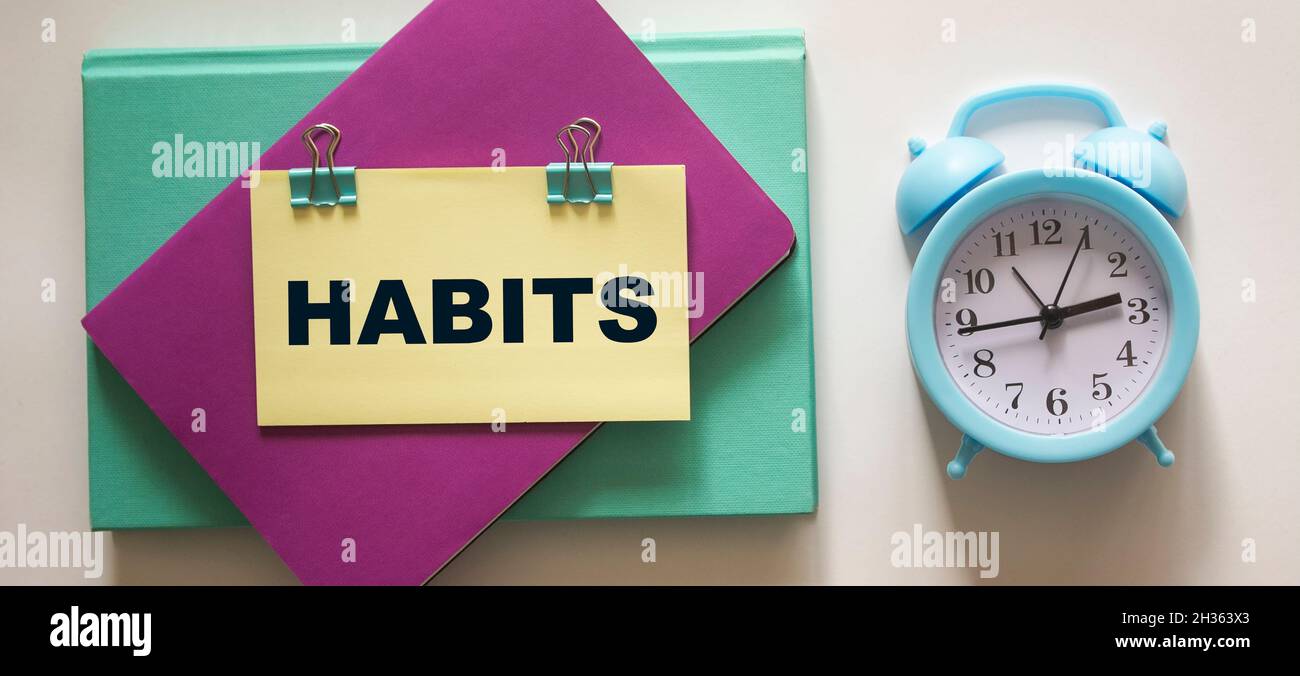 the word habit is written on a sticker that lies on colored diaries ...