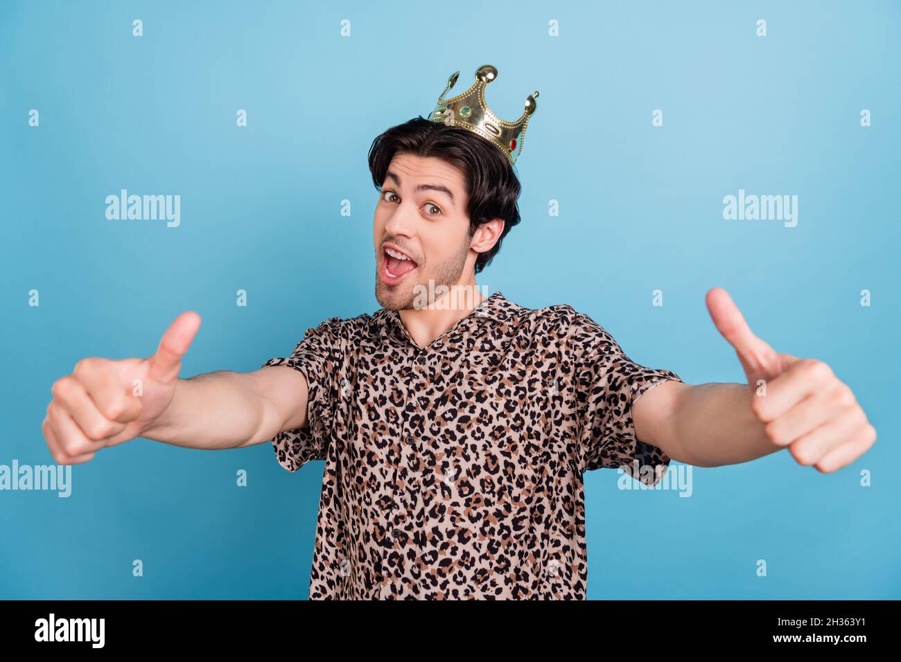 Portrait of attractive cool cheerful guy wearing crown giving two ...