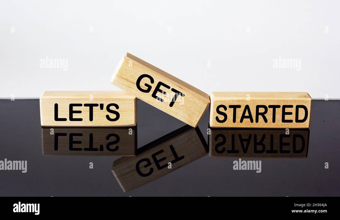 let's get started text on wood block and black and white background ...