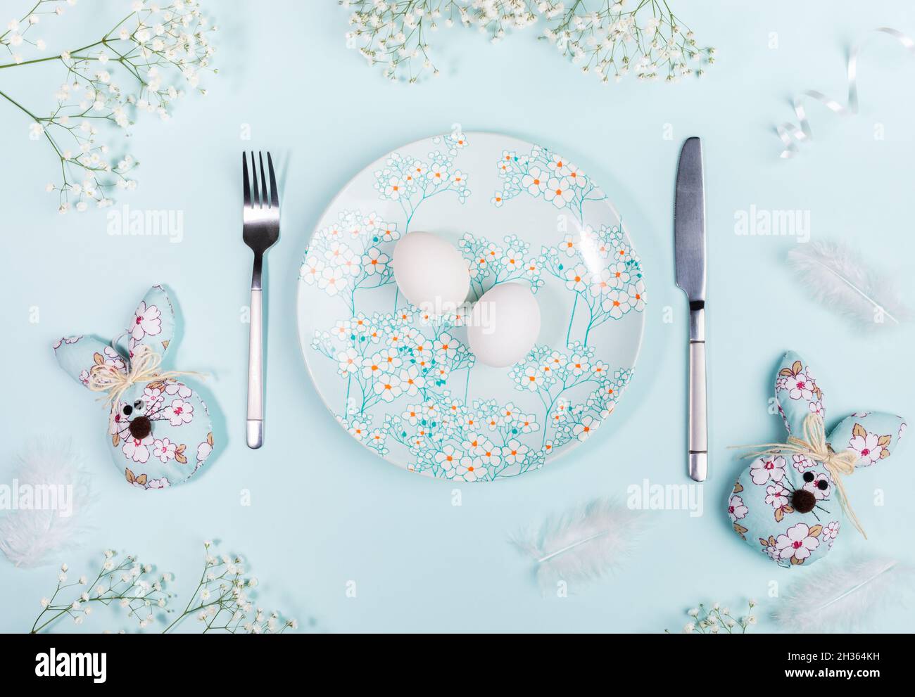 Flat lay Easter table setting with white eggs on plate with spring ...