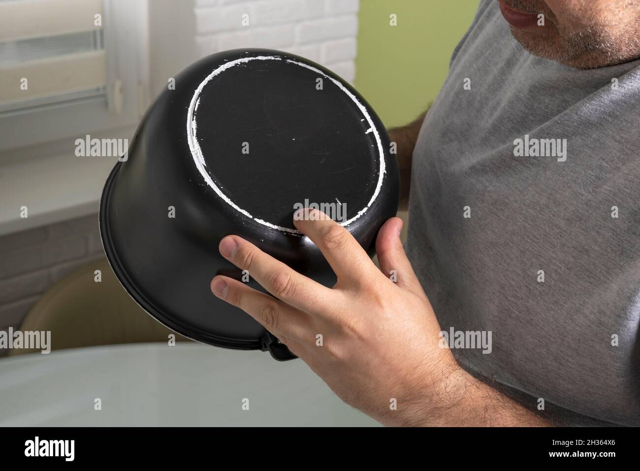 a man holding a non-stick pan with a damaged coating Stock Photo - Alamy