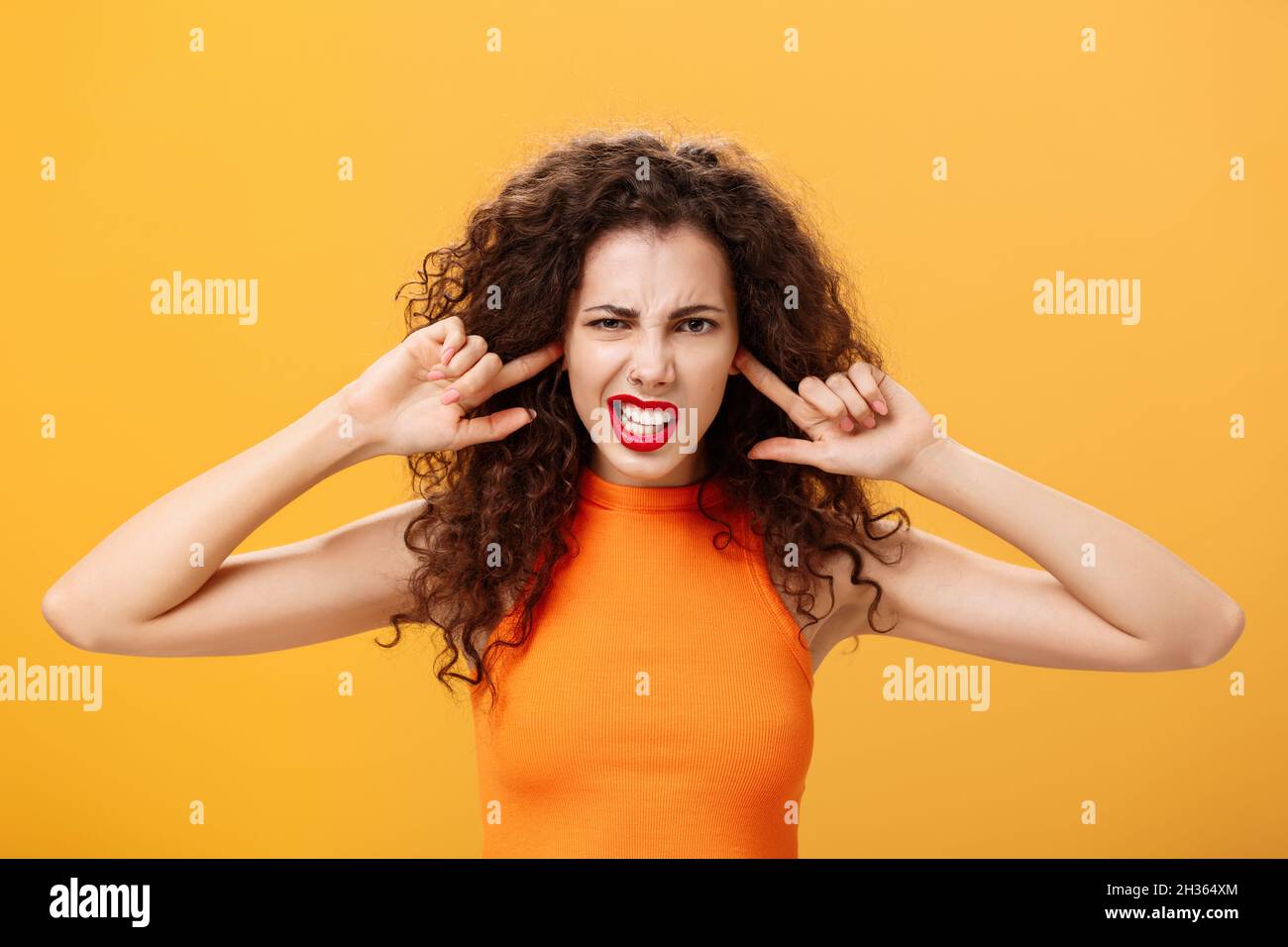 Waist Up Shot Of Irritated Bothered Stylish Woman With Curly Hair And