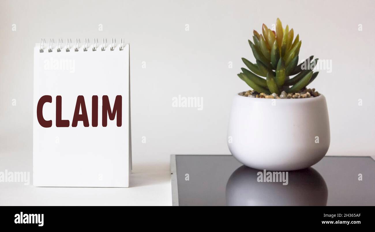 The word CLAIM is written on the pad. A cactus stands on a white and ...