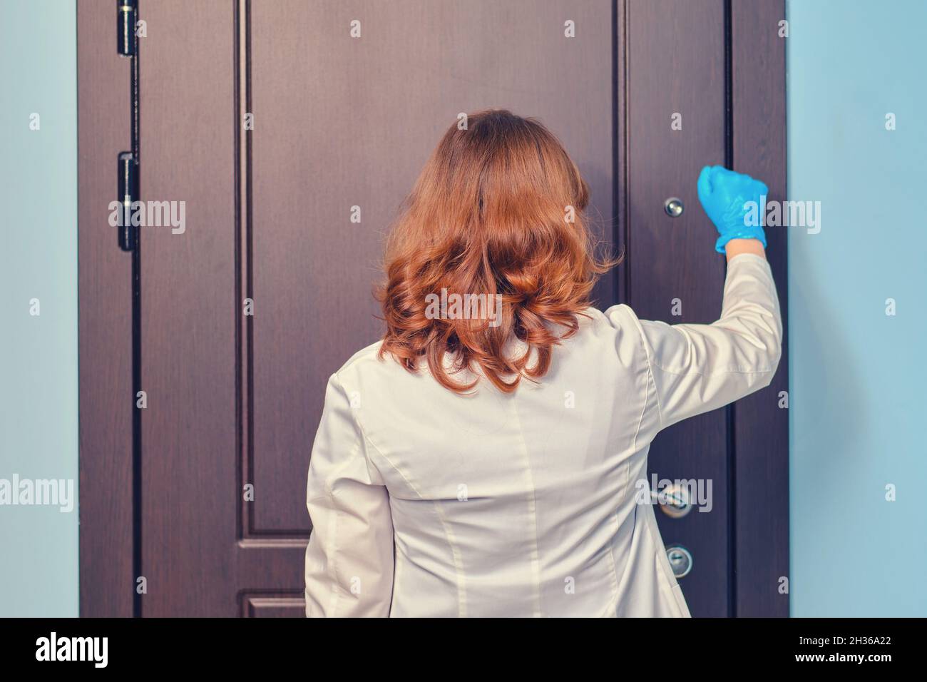 Woman doctor knocks on the door of the apartment when visiting a ...