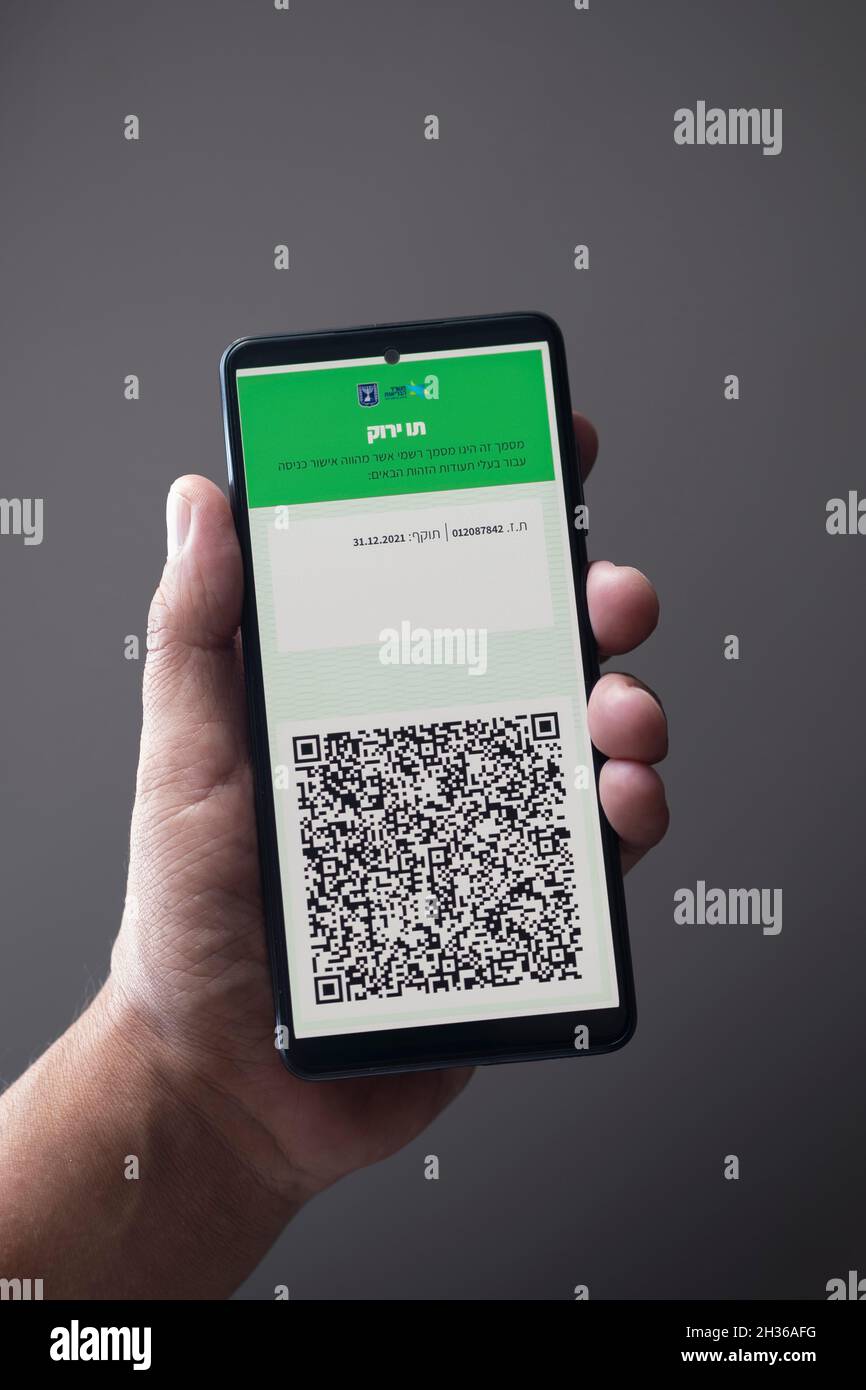 Man holds a smart phone which shows QR code of the Israeli Green Pass ...