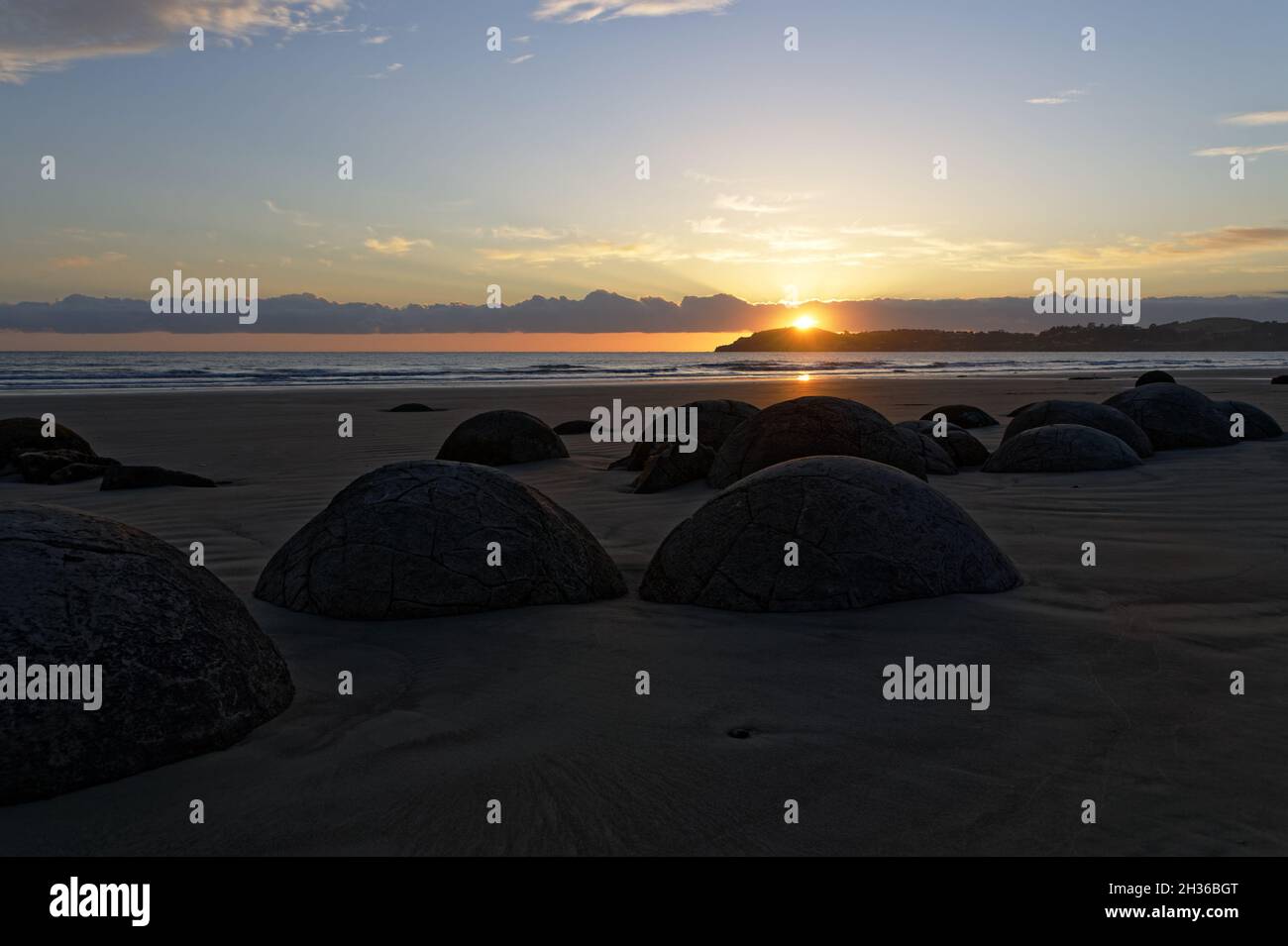 Moeraki Boulders are surrounded by water as the sun comes up. These ...
