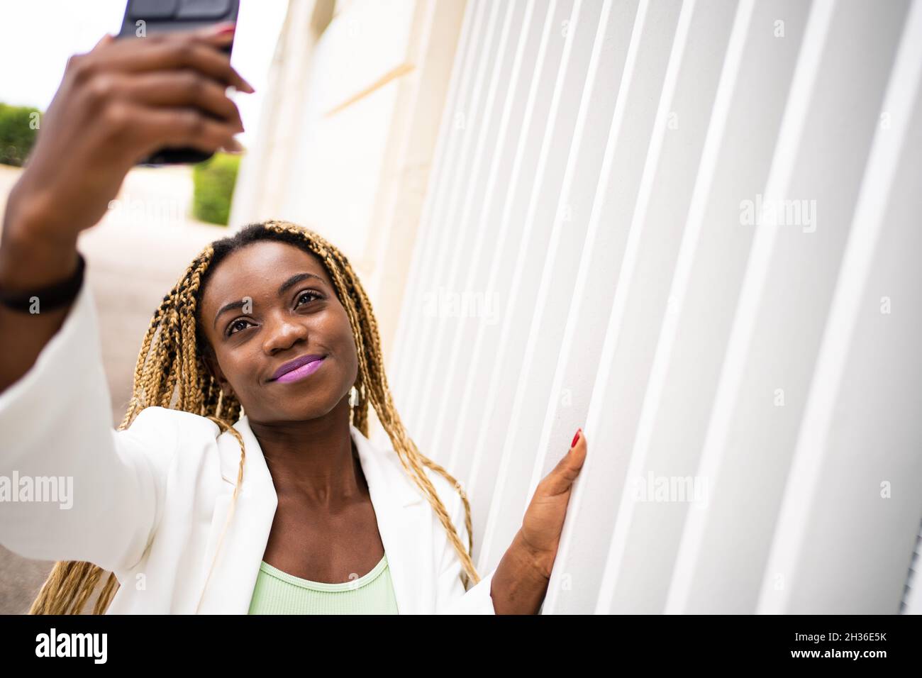 Smiling african woman taking a selfie with the mobile while standing ...