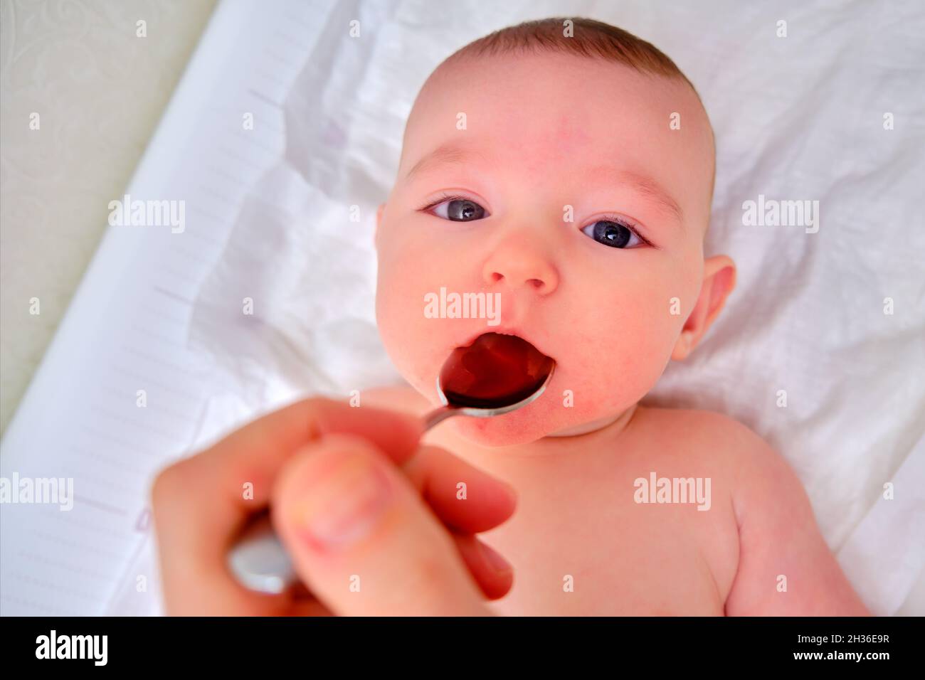 The mother gives the medicine Infant baby in the mouth on a spoon, oral ...