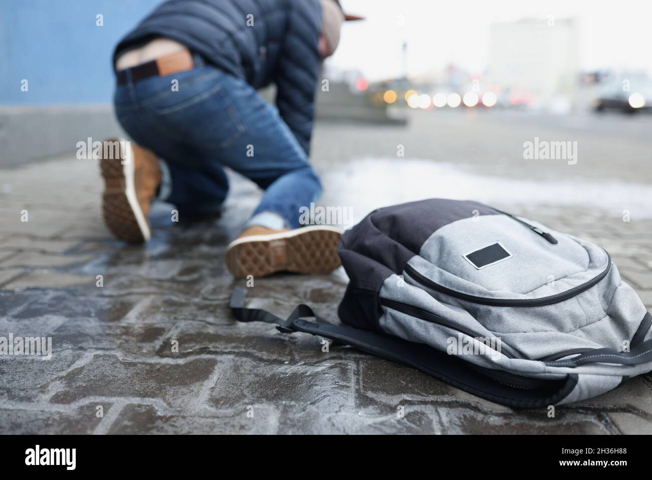 Backpack lying on slippery paving slabs near falling man closeup Stock ...