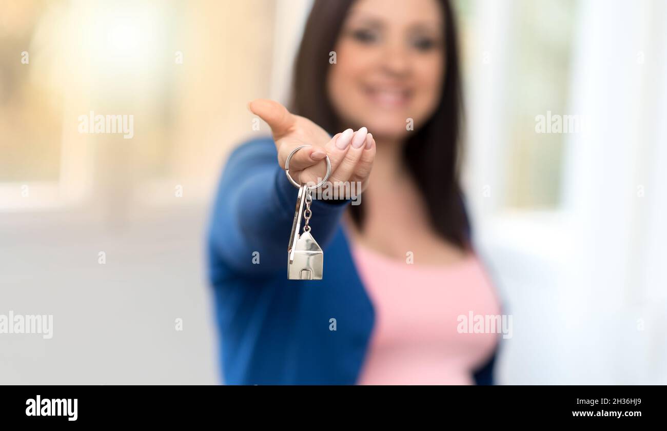 Young woman holding out house keys, light effect Stock Photo - Alamy