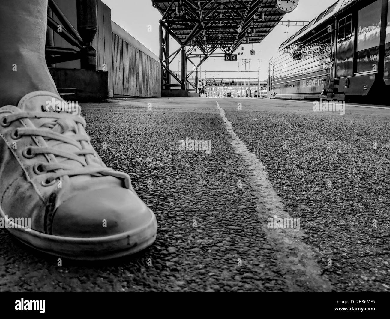 Grayscale close up of a shoe on an asphalt ground Stock Photo - Alamy