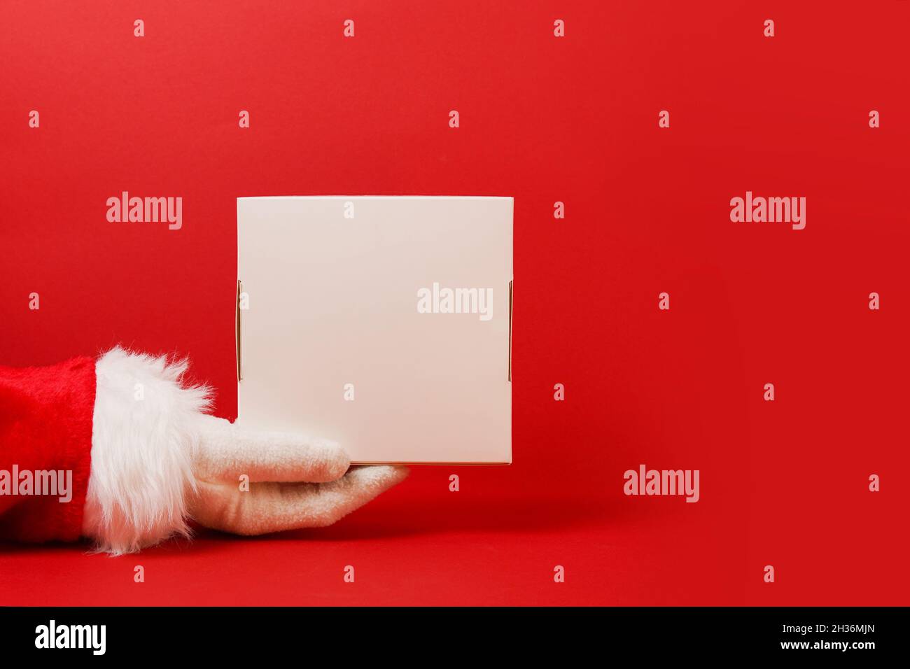 Santa Claus holding and offering a white gift box on his hand. red ...