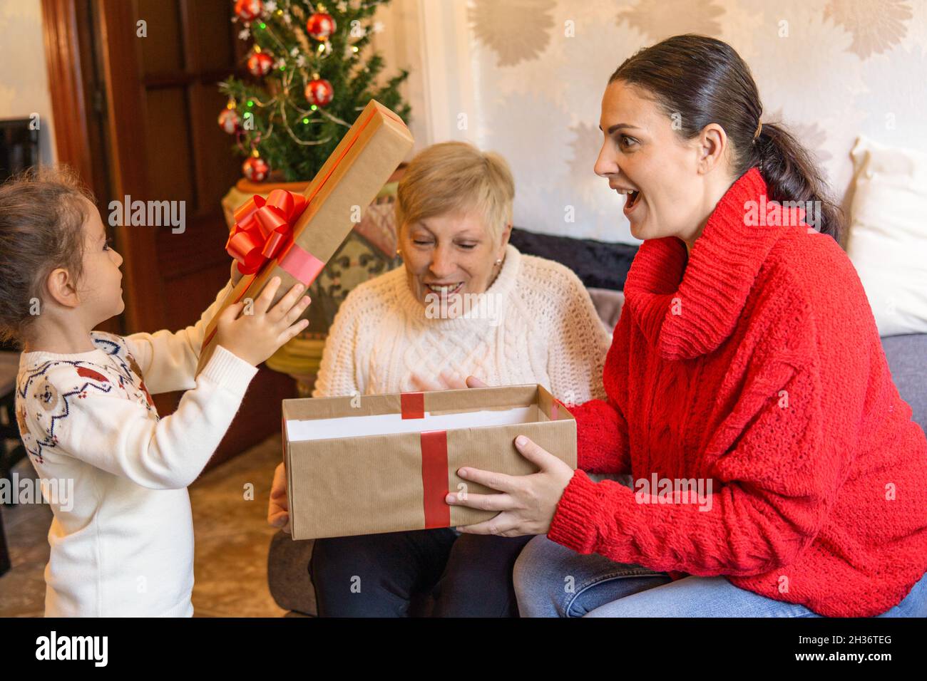Child opening a Christmas present with his family. Gift wrapped Stock ...