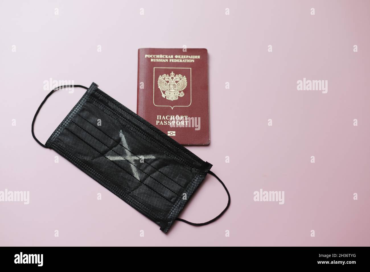 Black face mask with white cross and Russian foreign passport to travel ...